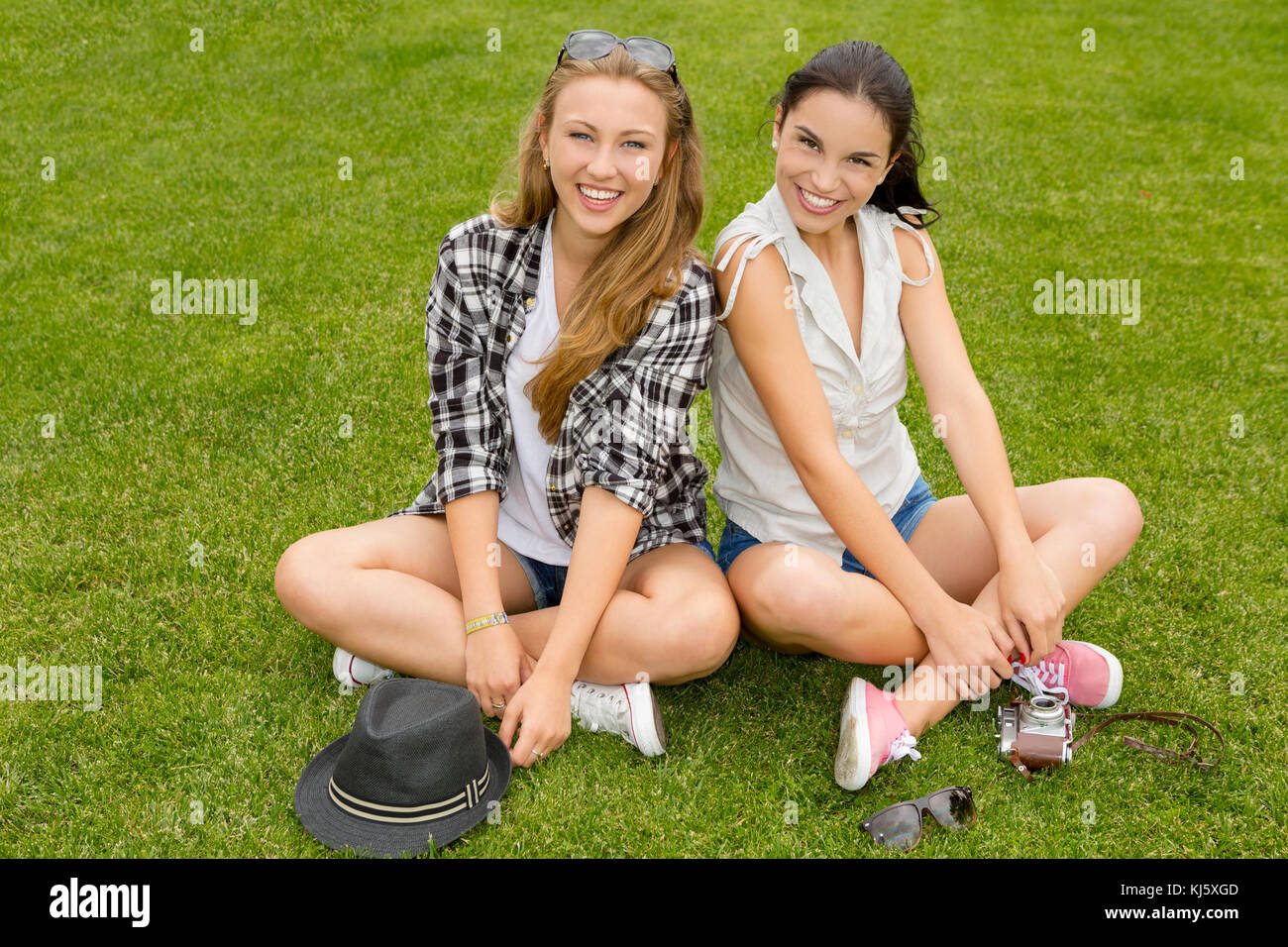 Female best friends sitting on the grass and having a good time Stock ...
