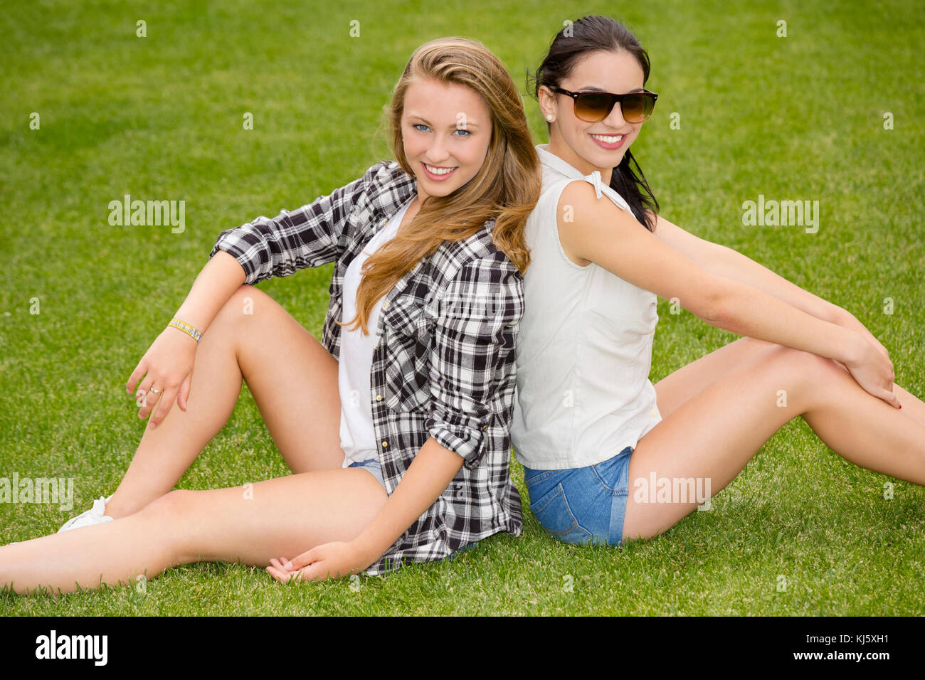 Female best friends sitting on the grass and having a good time Stock ...