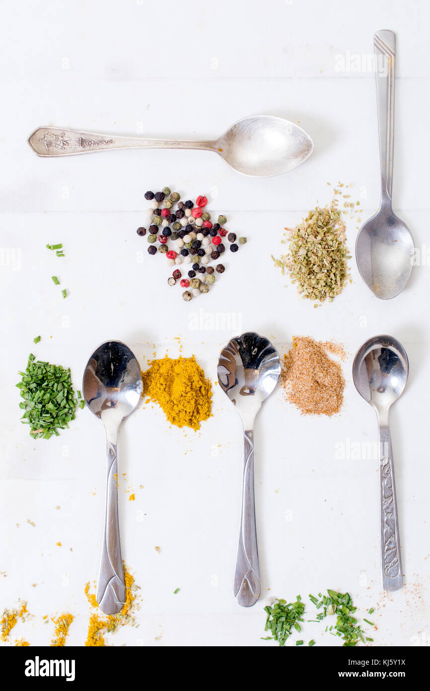 Empty different spoons and different spices from above on white ...