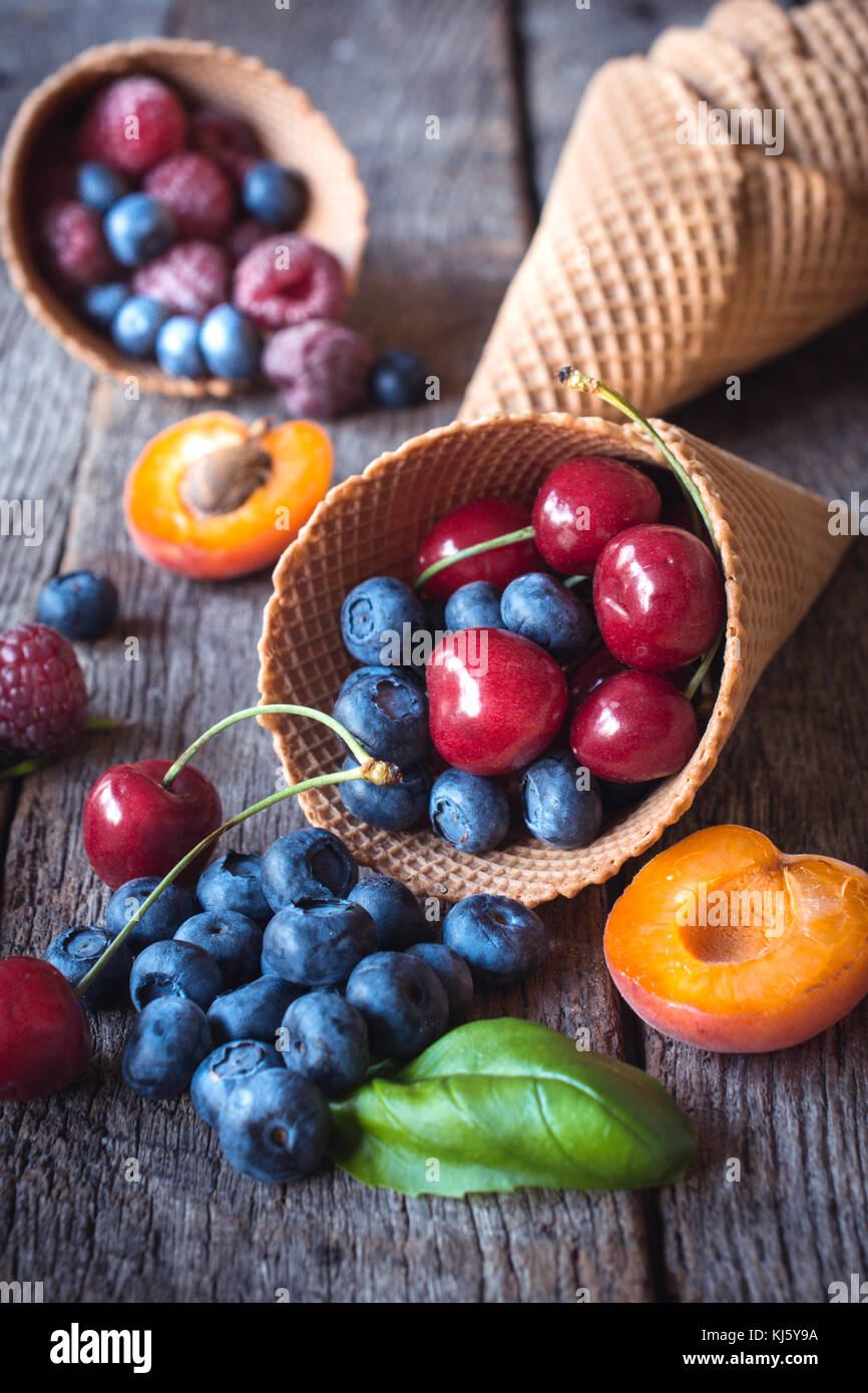Fresh fruits in the ice cream cone on wooden background,selective focus ...