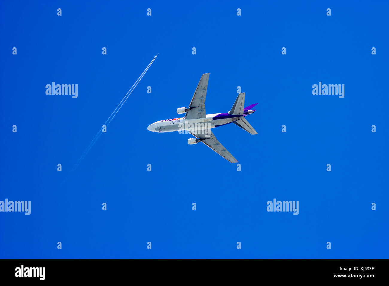 Low-flying jet plane passing a higher flying jet's contrail Stock Photo ...