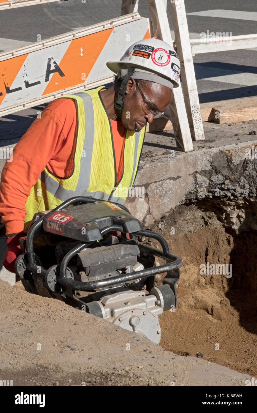 A construction worker working on underground piping using a compactor ...