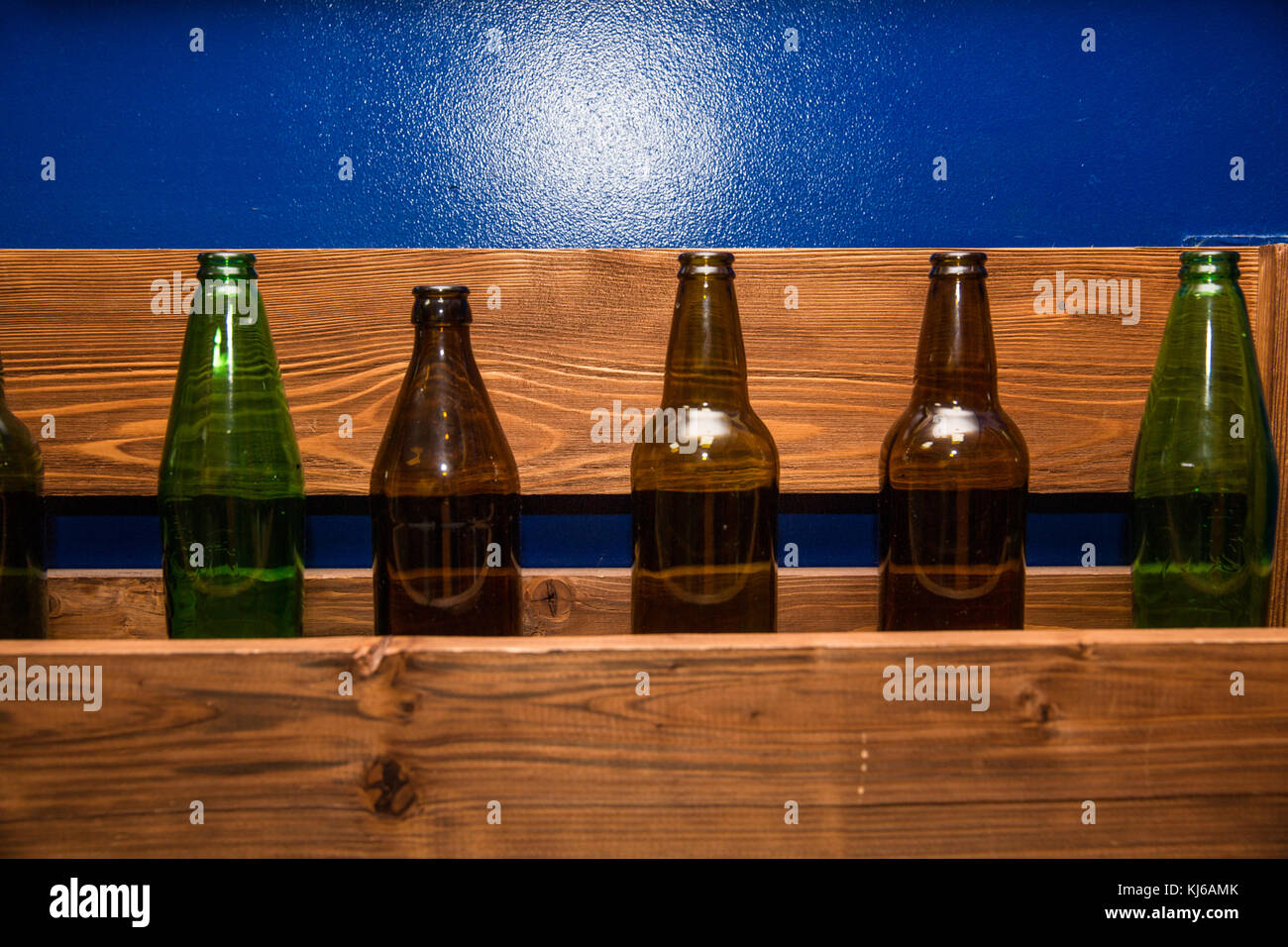 Set of empty bottles on wooden shelf over blue wall Stock Photo - Alamy