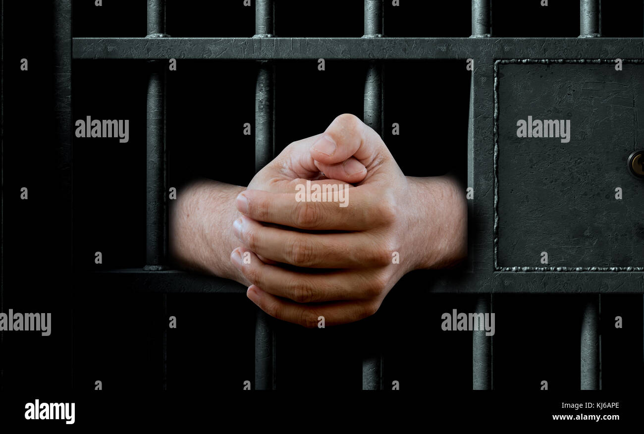 A closeup of a dimly lit prison holding cell door with arms reaching ...