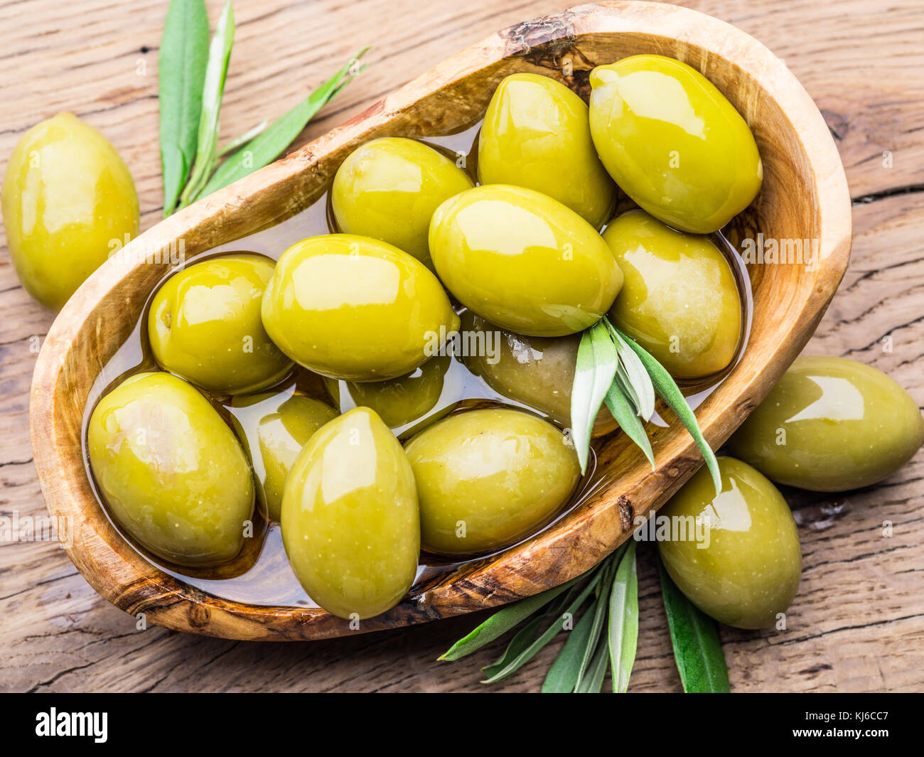 Whole table olives in the wooden bowl on the table. Top view Stock ...