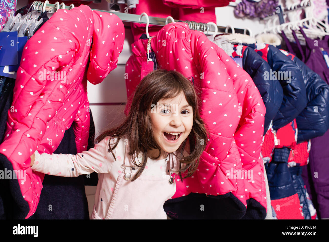 The little girl having fun in clothing store Stock Photo - Alamy