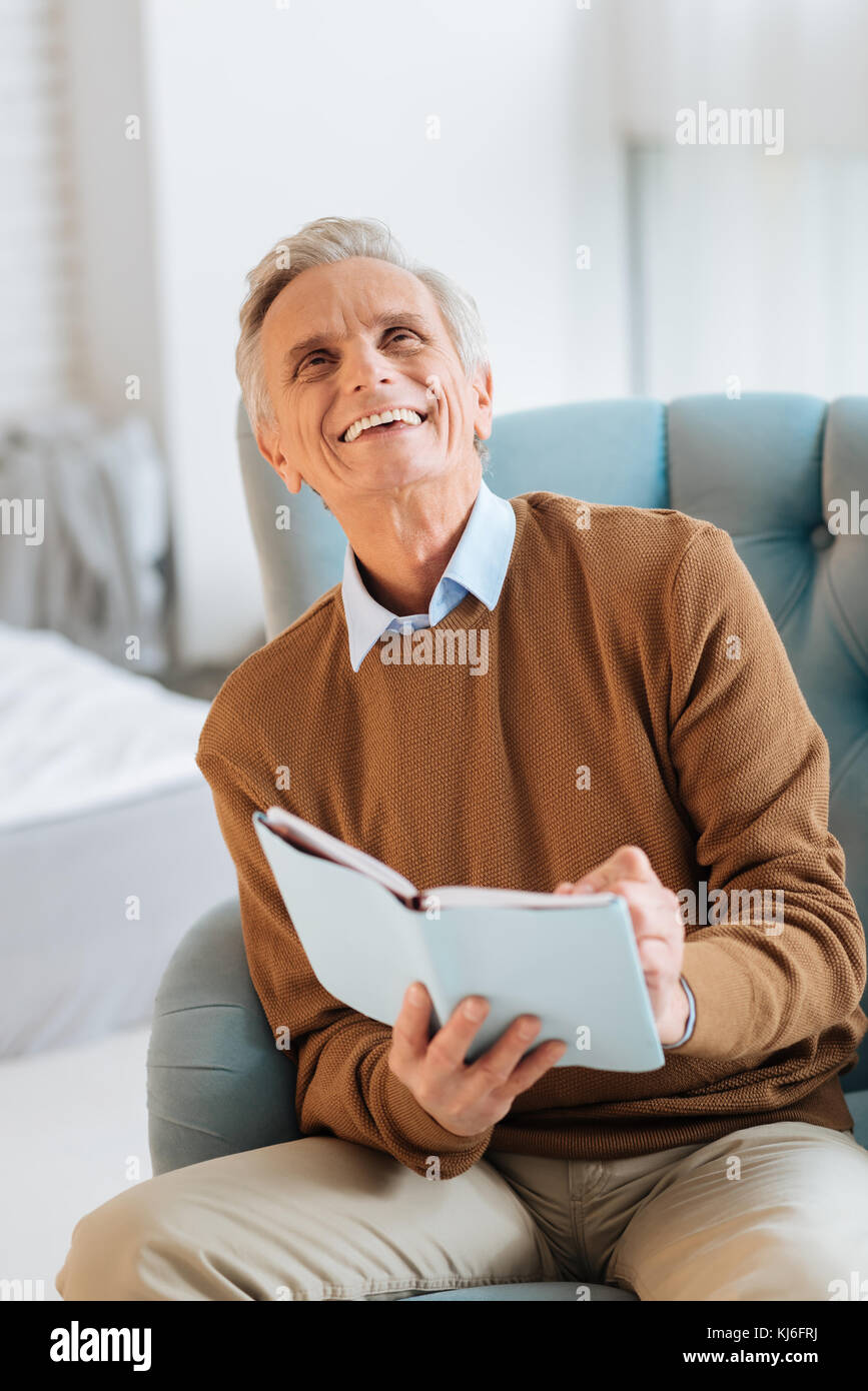 Radiant old man smiling while taking notes Stock Photo - Alamy