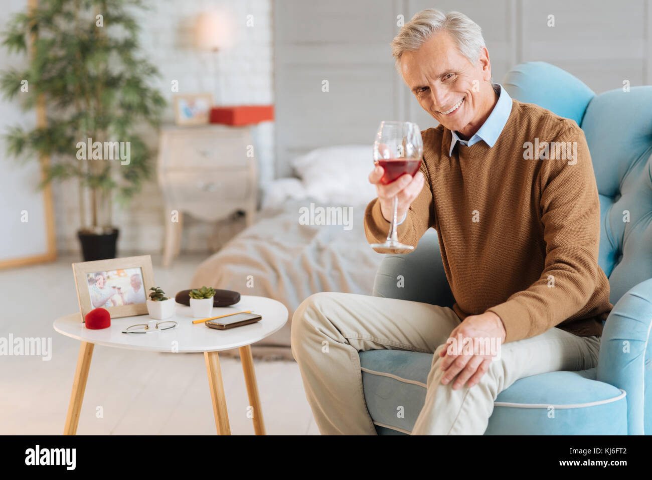 Joyful senior gentleman with glass of wine smiling into camera Stock ...
