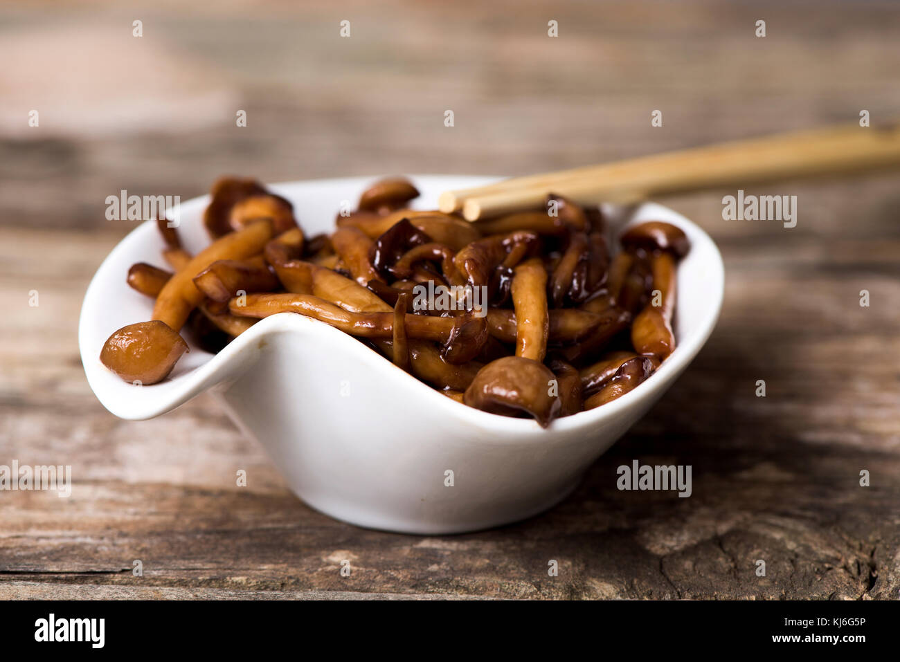 a white ceramic bowl with sauteed japanese bunapi-shimeji mushrooms ...