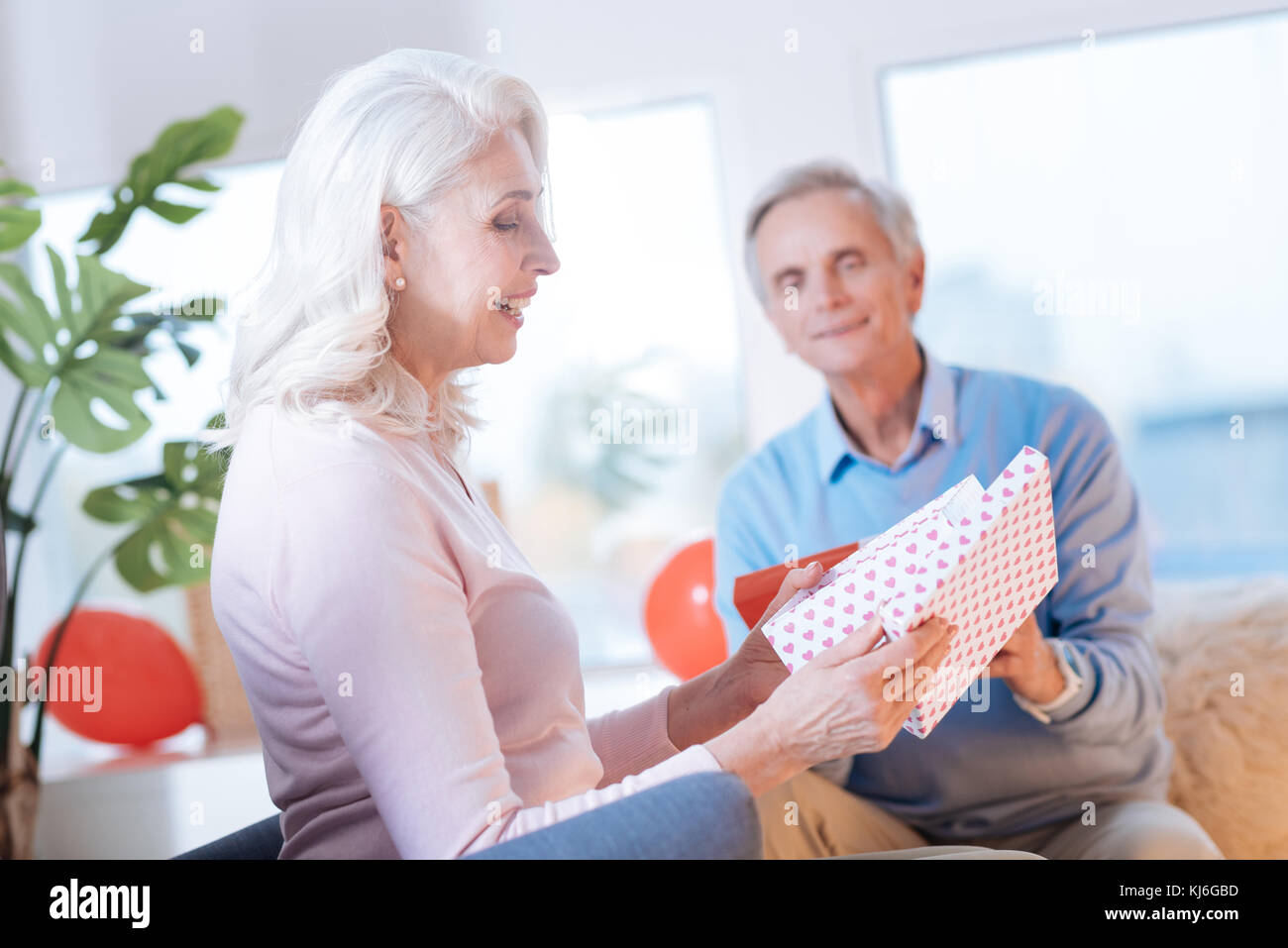 Surprised senior lady opening her present Stock Photo - Alamy