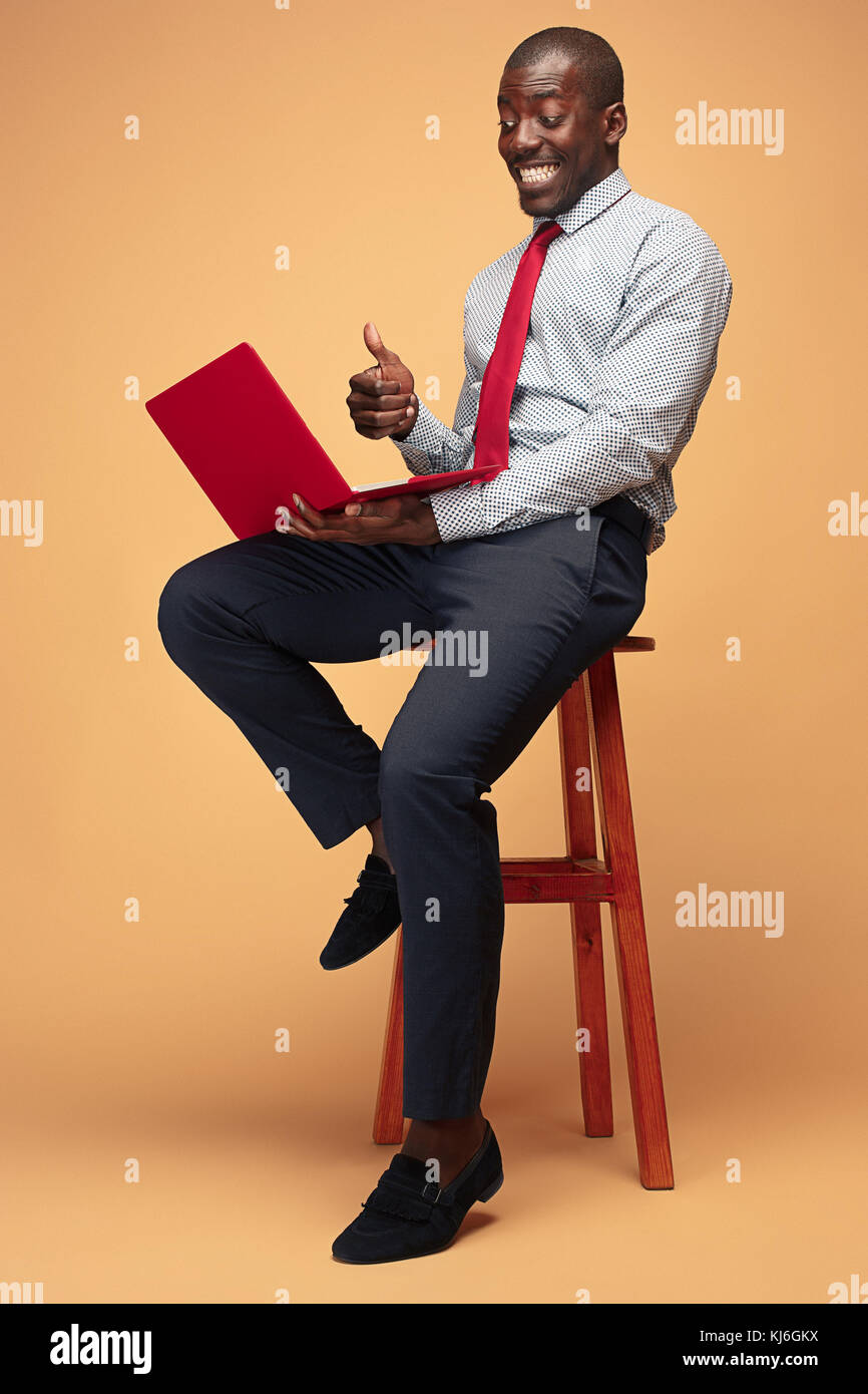 Handsome Afro American man sitting and using a laptop Stock Photo - Alamy