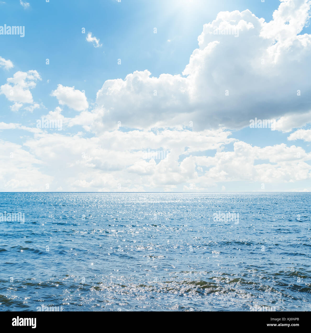 blue sea with sun reflections and blue sky with clouds Stock Photo - Alamy