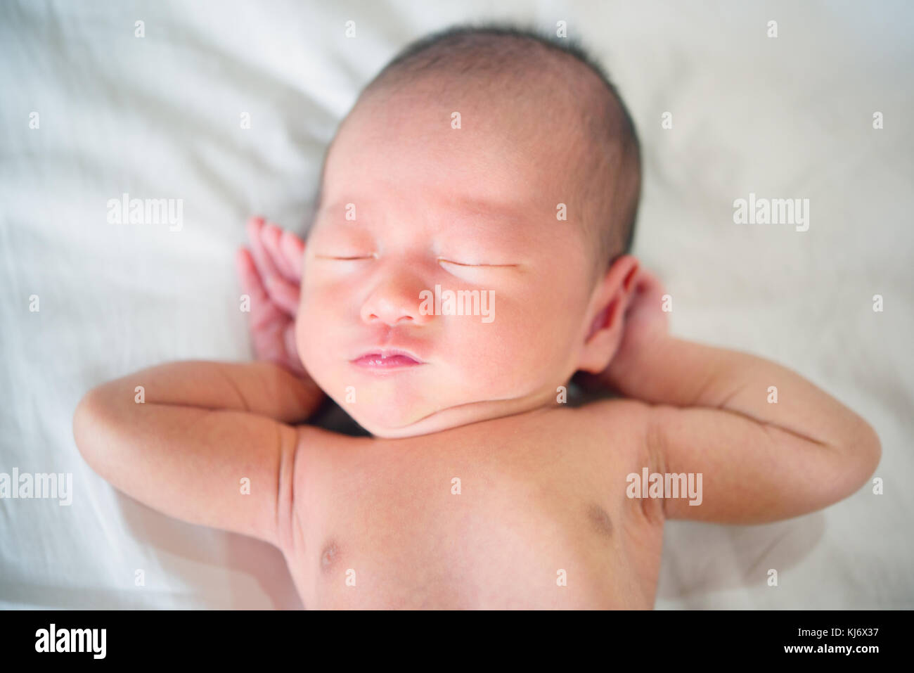 Newborn baby boy waking up and stretching in bed Stock Photo - Alamy