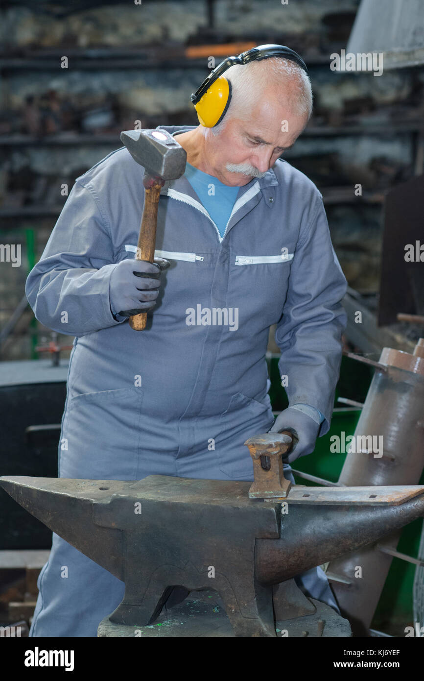 Metalworker using hammer over anvil Stock Photo - Alamy