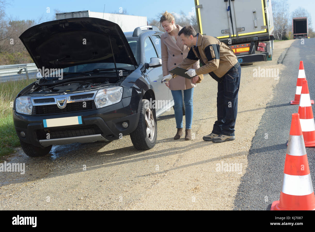 Recovery man with lady broken down by the road Stock Photo - Alamy