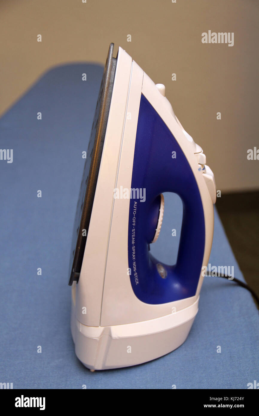 An iron sitting on an ironing board Stock Photo - Alamy