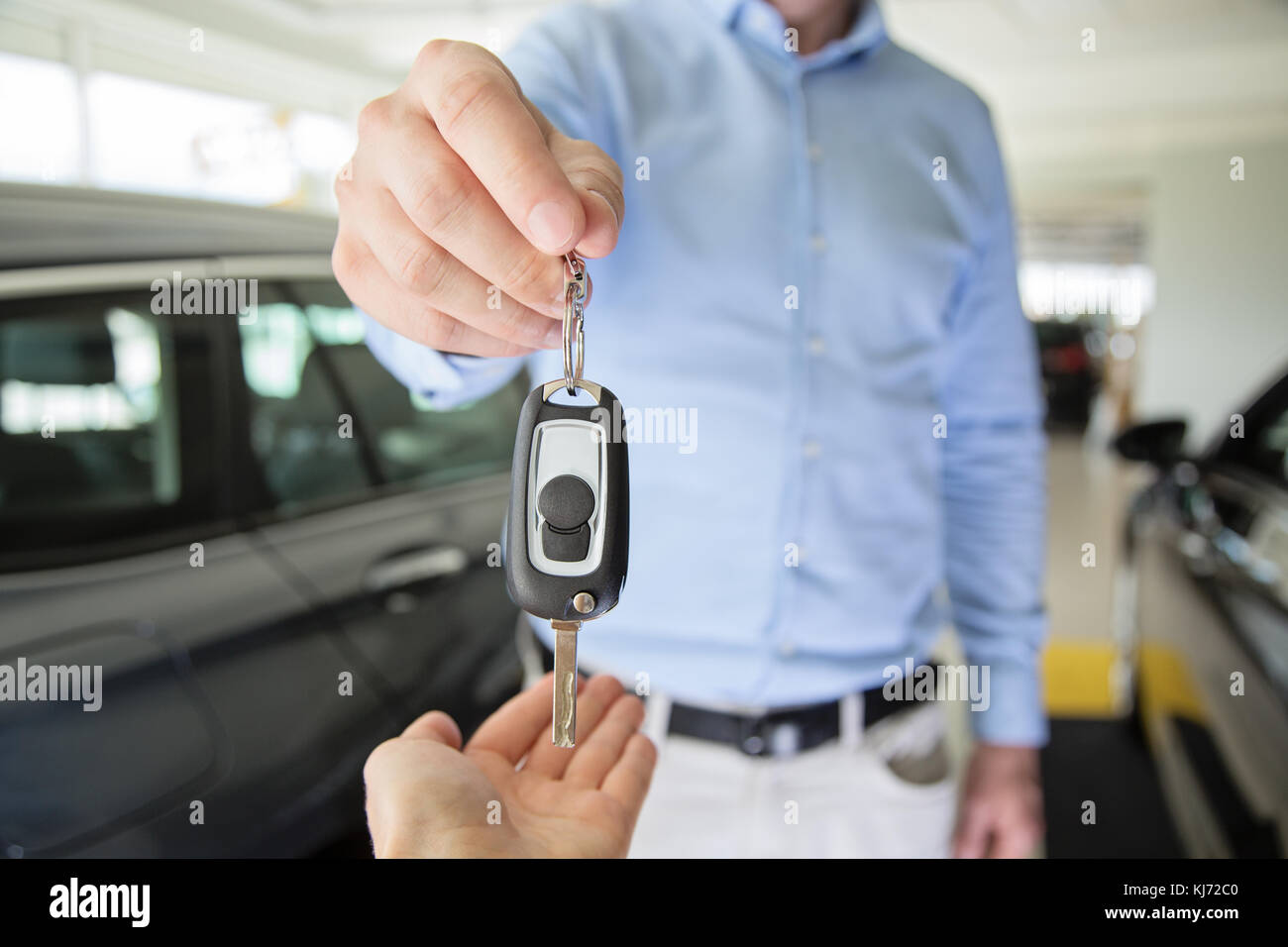 Close photo of male car dealer hand giving a car key to a female person ...