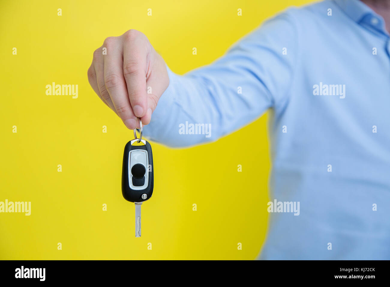 close up photo of male hand holding a car key. Person is wearing a blue ...