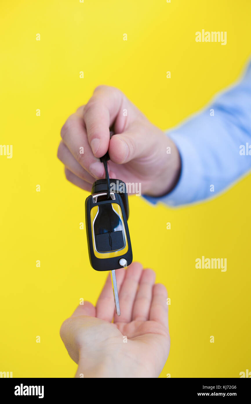 close up photo of male hand holding a car key. Person is wearing a blue ...