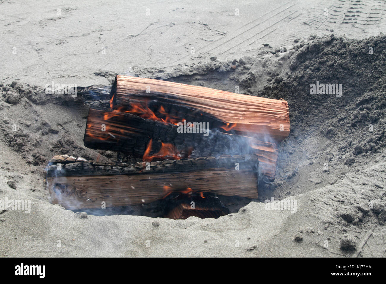 A wood fire burning on the beach in the sand Stock Photo - Alamy