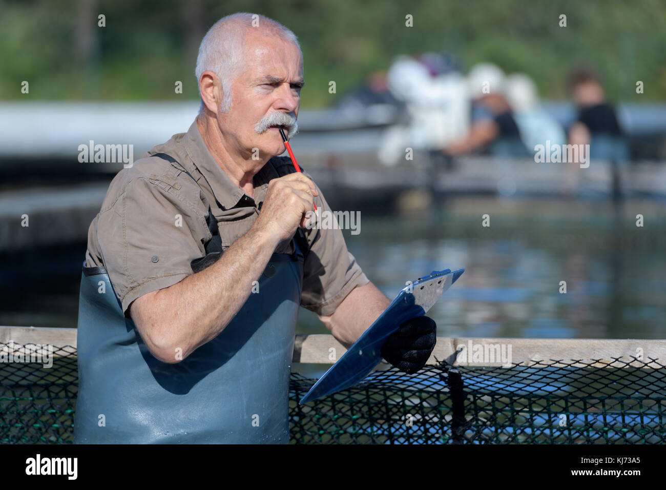 man with clipboard standing by a river writing something Stock Photo ...