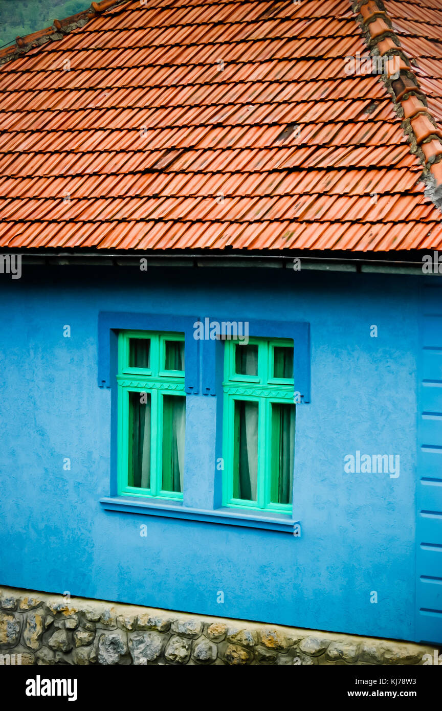 country side house vivid bright blue color wall with two green windows ...