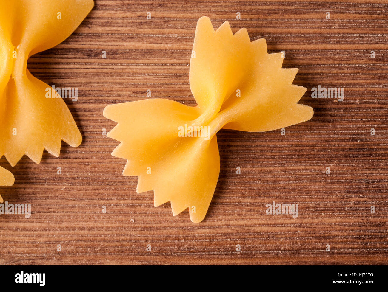single bow tie pasta on wooden background Stock Photo - Alamy