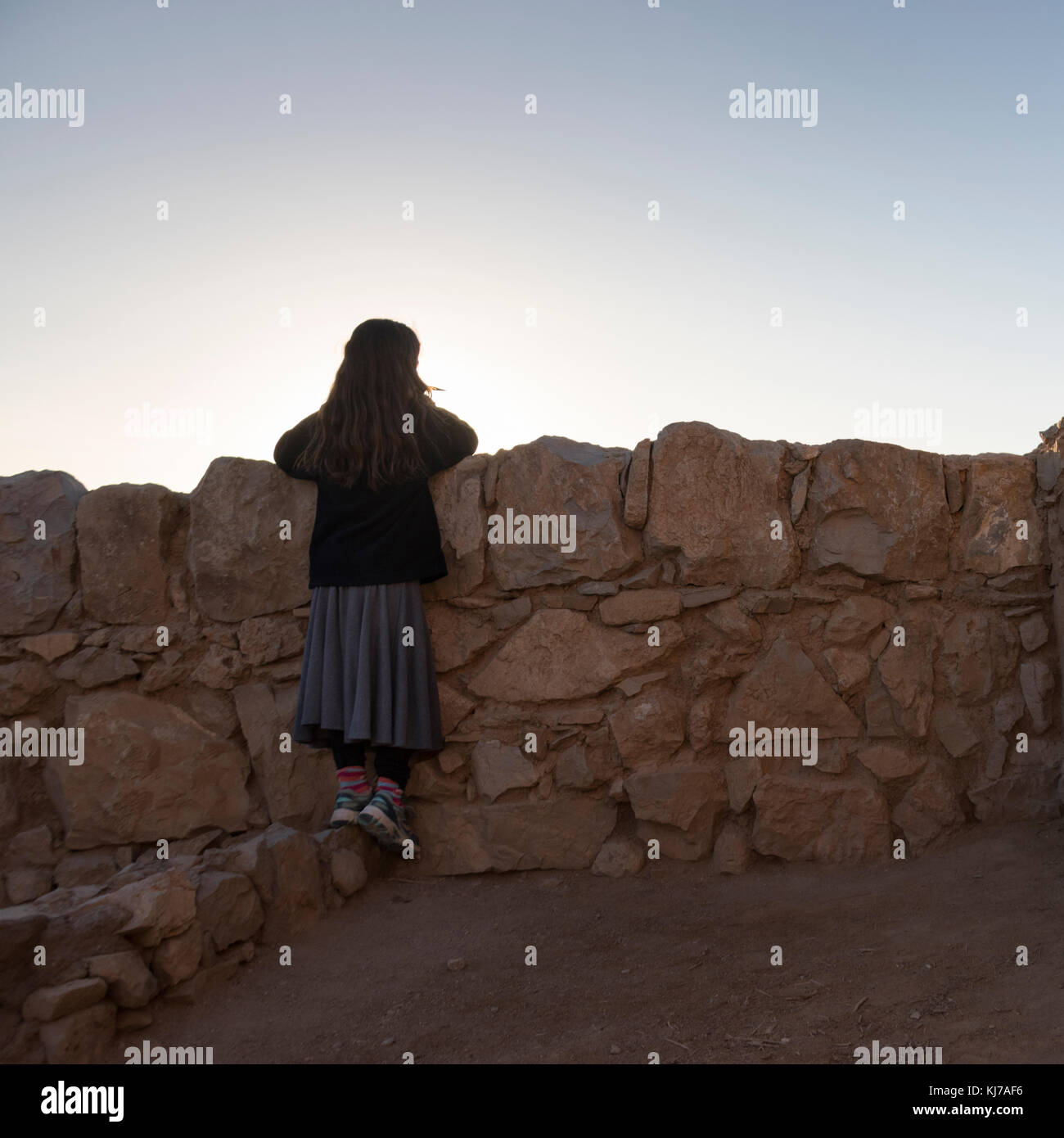 Rear view of girl leaning against wall at fort, Masada, Judean Desert ...