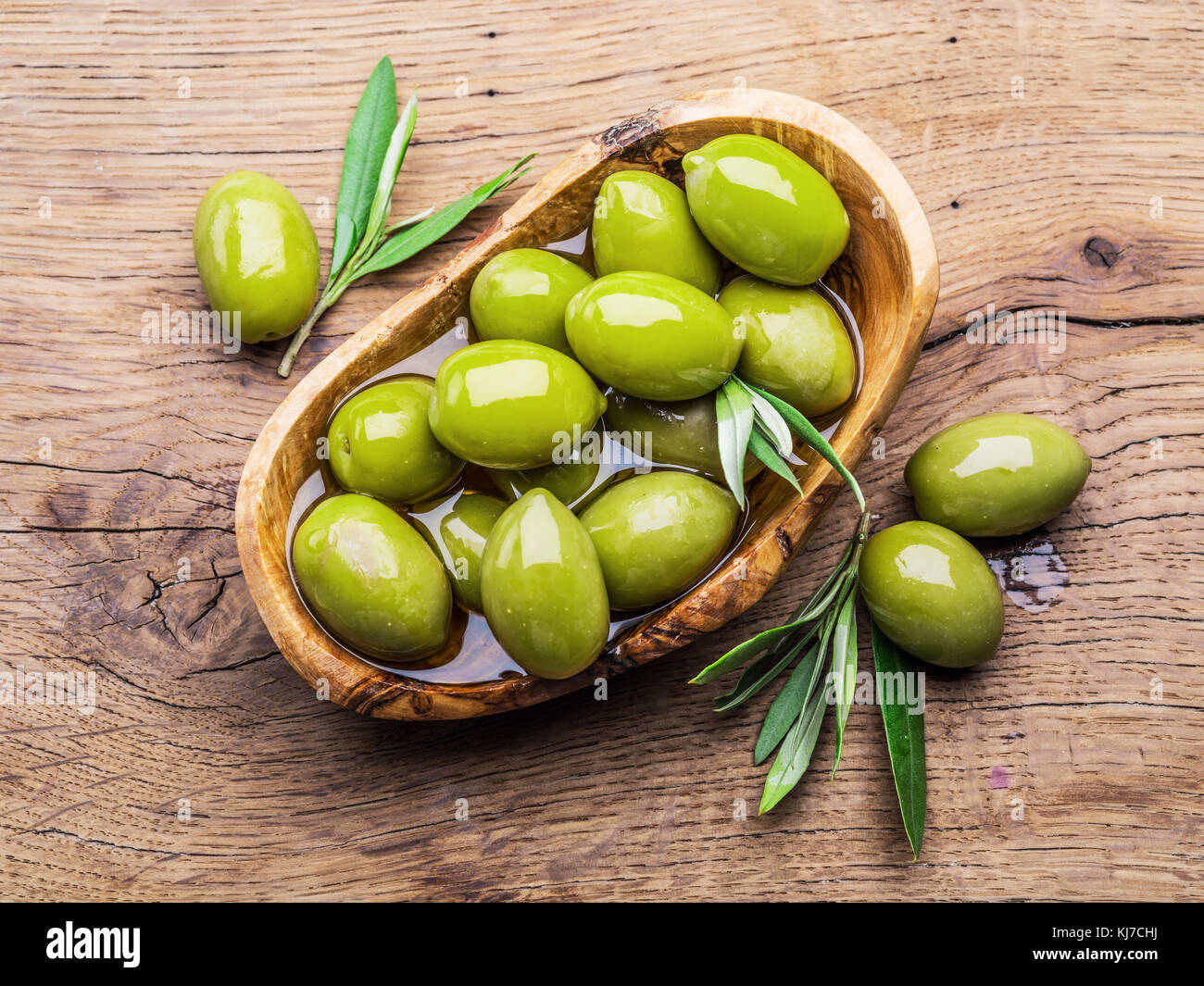 Whole table olives in the wooden bowl on the table. Top view Stock ...