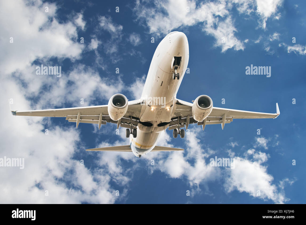 Low-flying civilian aircraft with landing gear against the blue cloudy ...