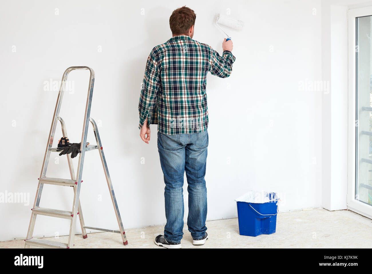 Young man painting a wall on white in a modern home Stock Photo - Alamy