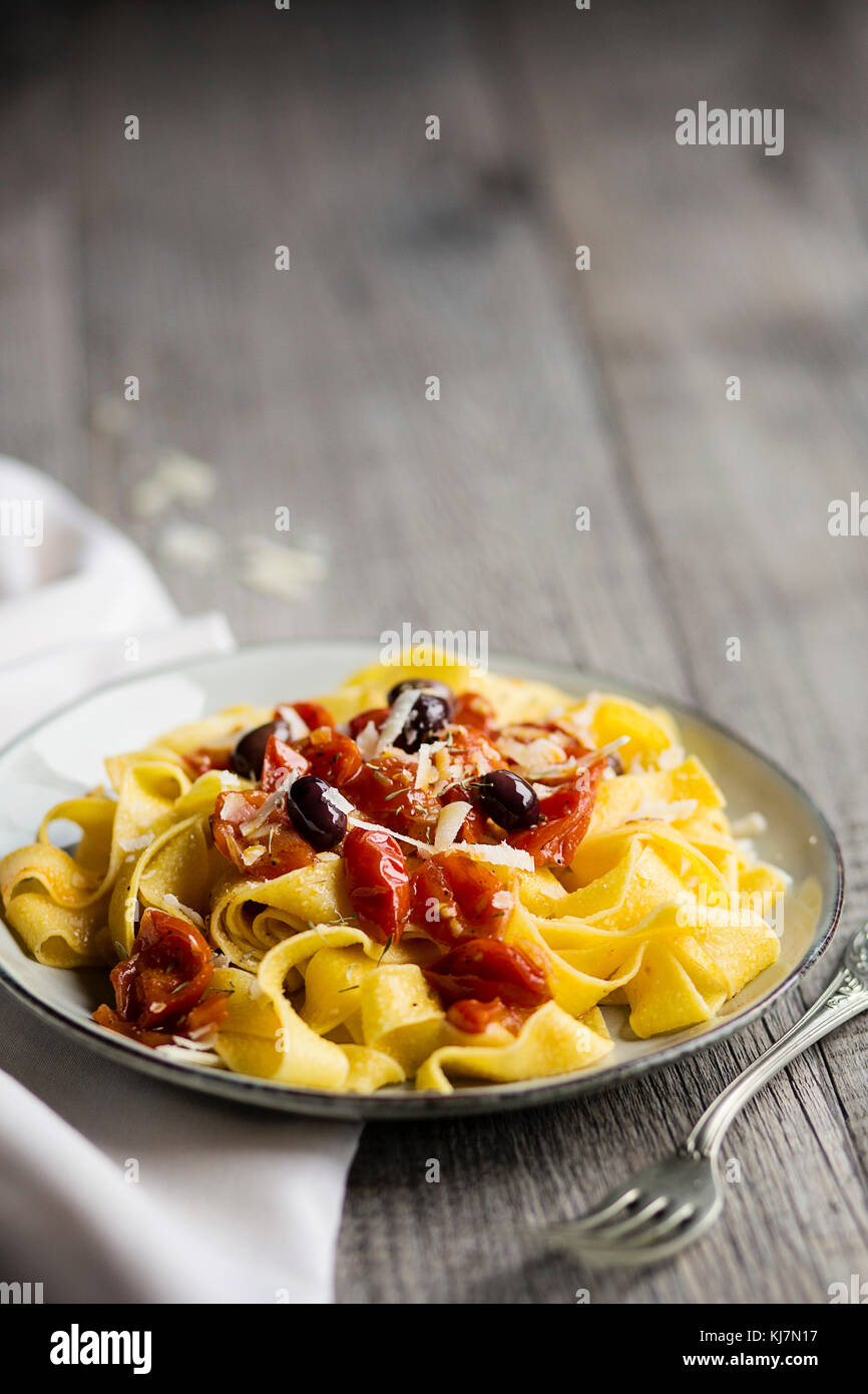 A typical italian dish pappardelle pasta with tomato sauce, olives and ...