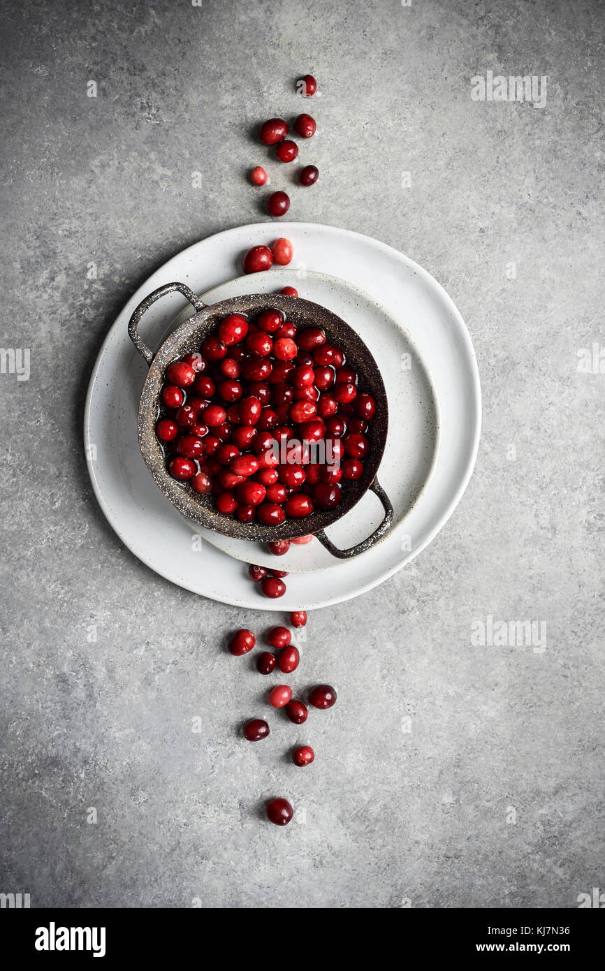 Metal bowl filled with cranberries on stack of plates with more ...