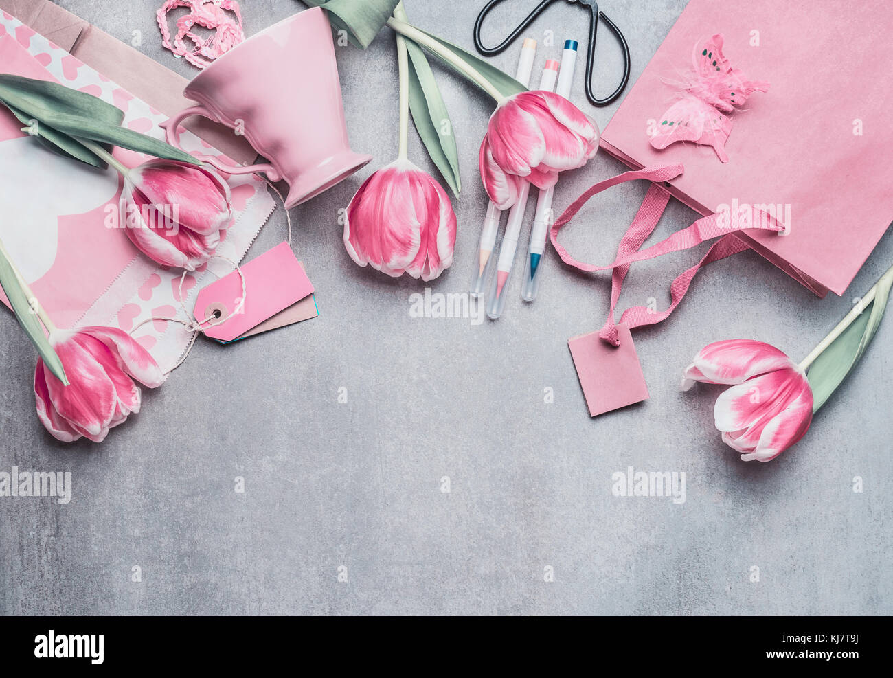 Springtime still life border with pastel pink tulips, hearts, mug m ...