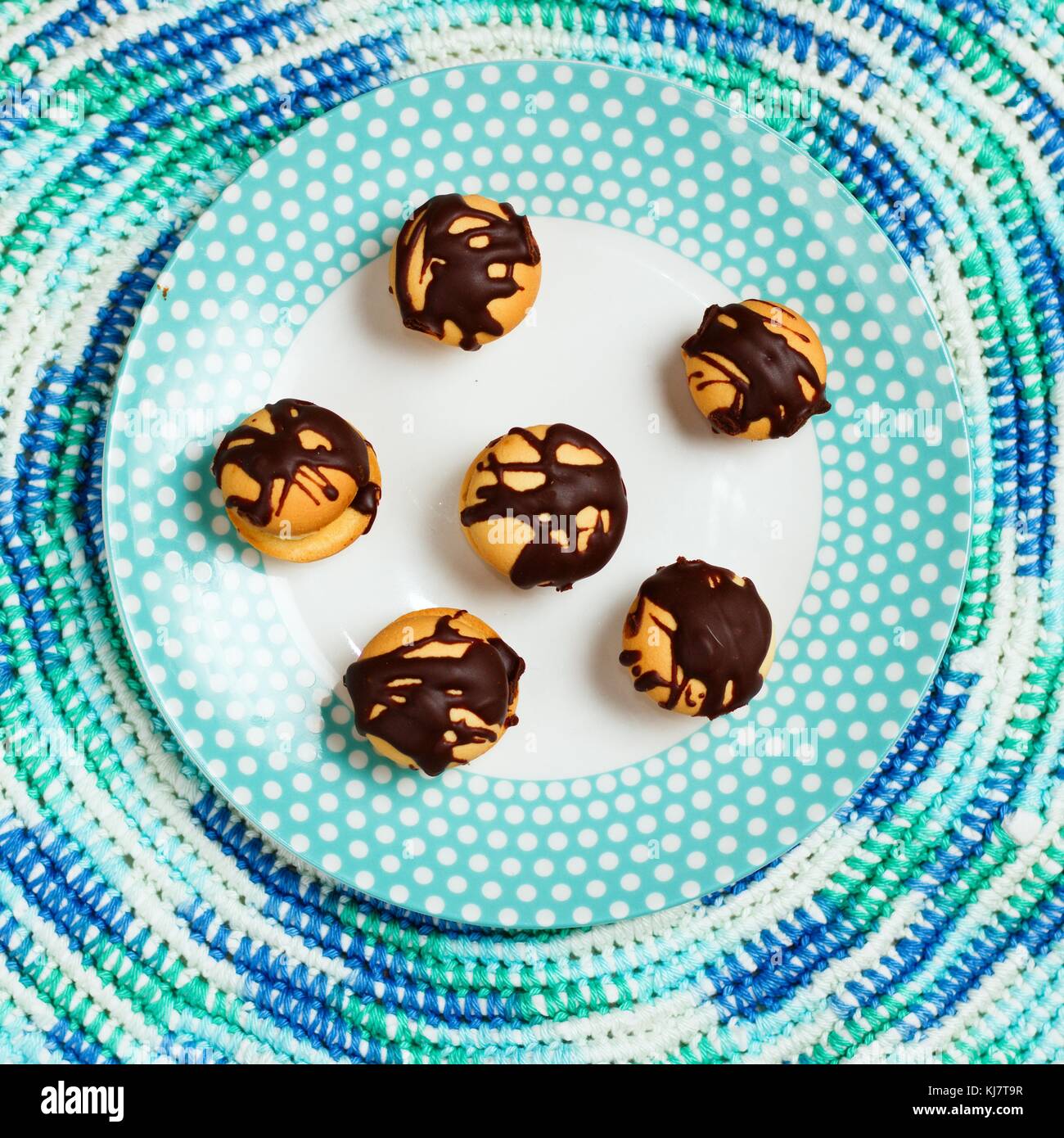 Top down view on small sweet pastries on a plate and knitted placemat ...