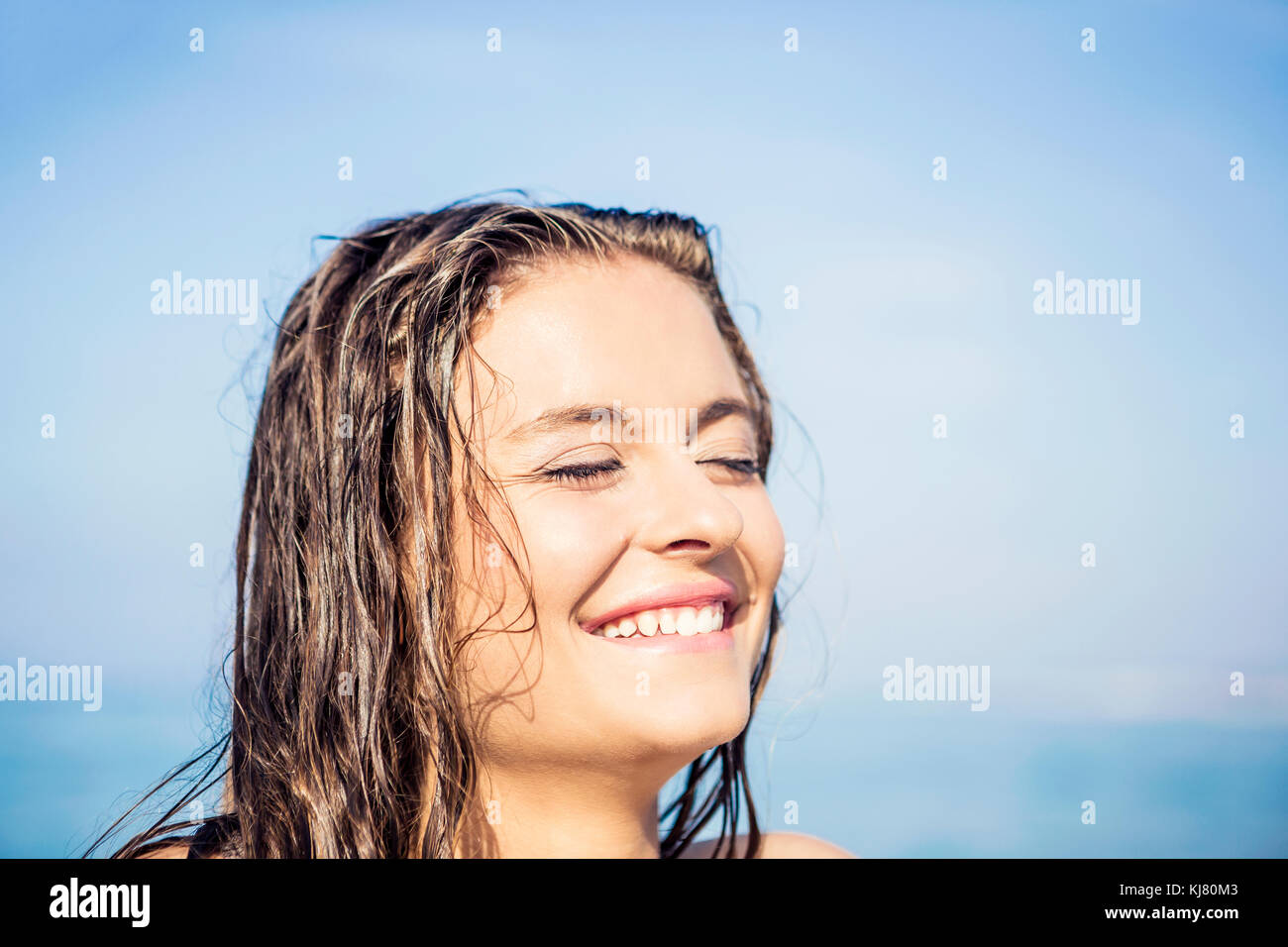 Outdoor portrait of a beautiful young woman with the ocean in the back ...