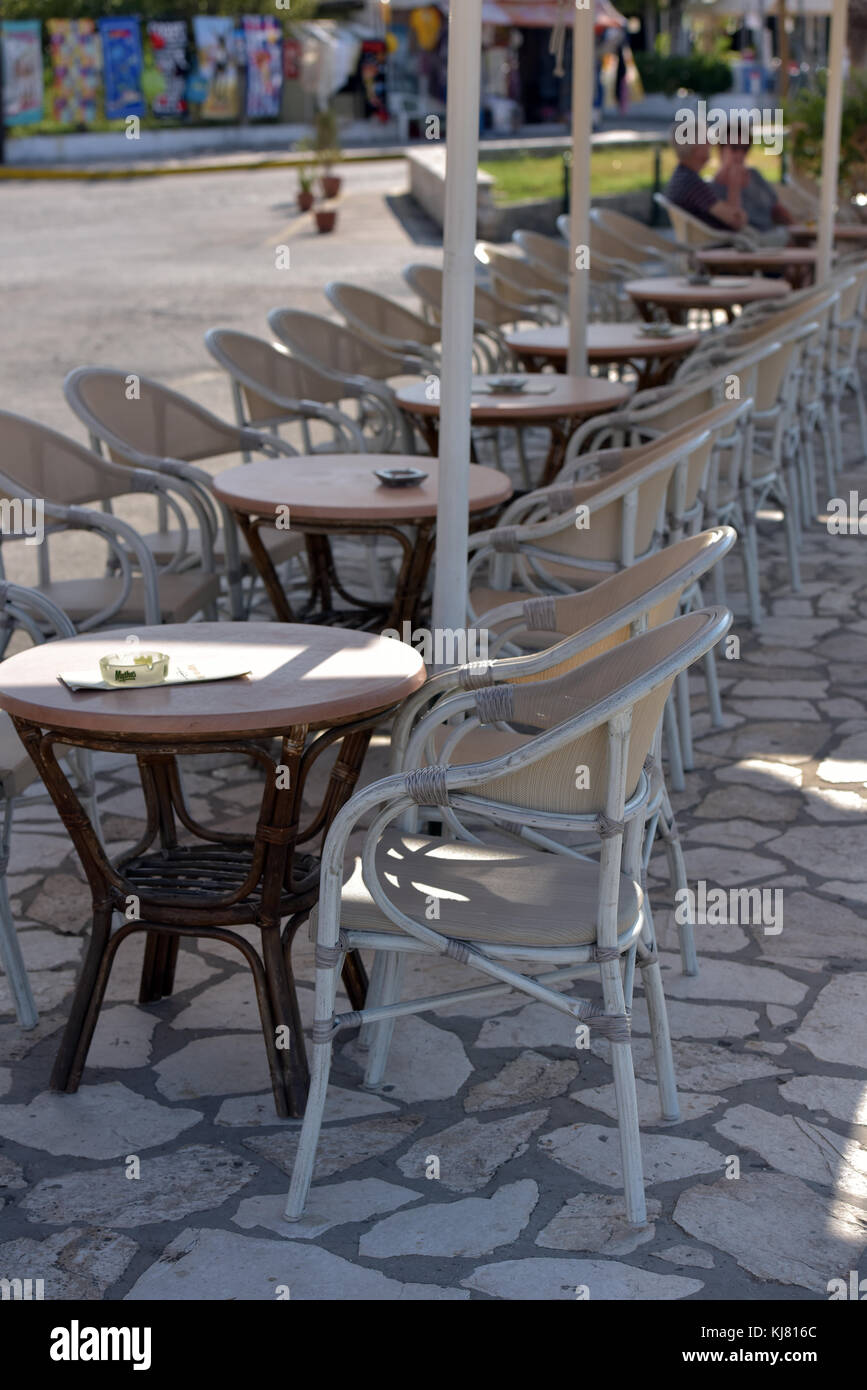 A long row or line of tables and chairs at a greek taverna with a ...