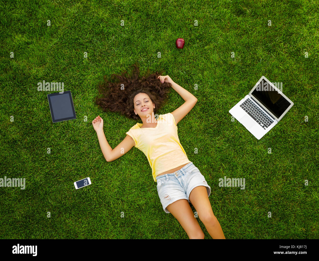 Beautiful and happy young woman lying on the grass surrounded by ...
