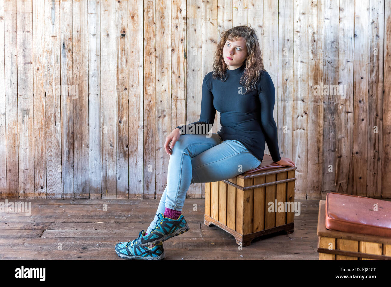 Side view of one, lonely, alone young woman sitting on small bench ...