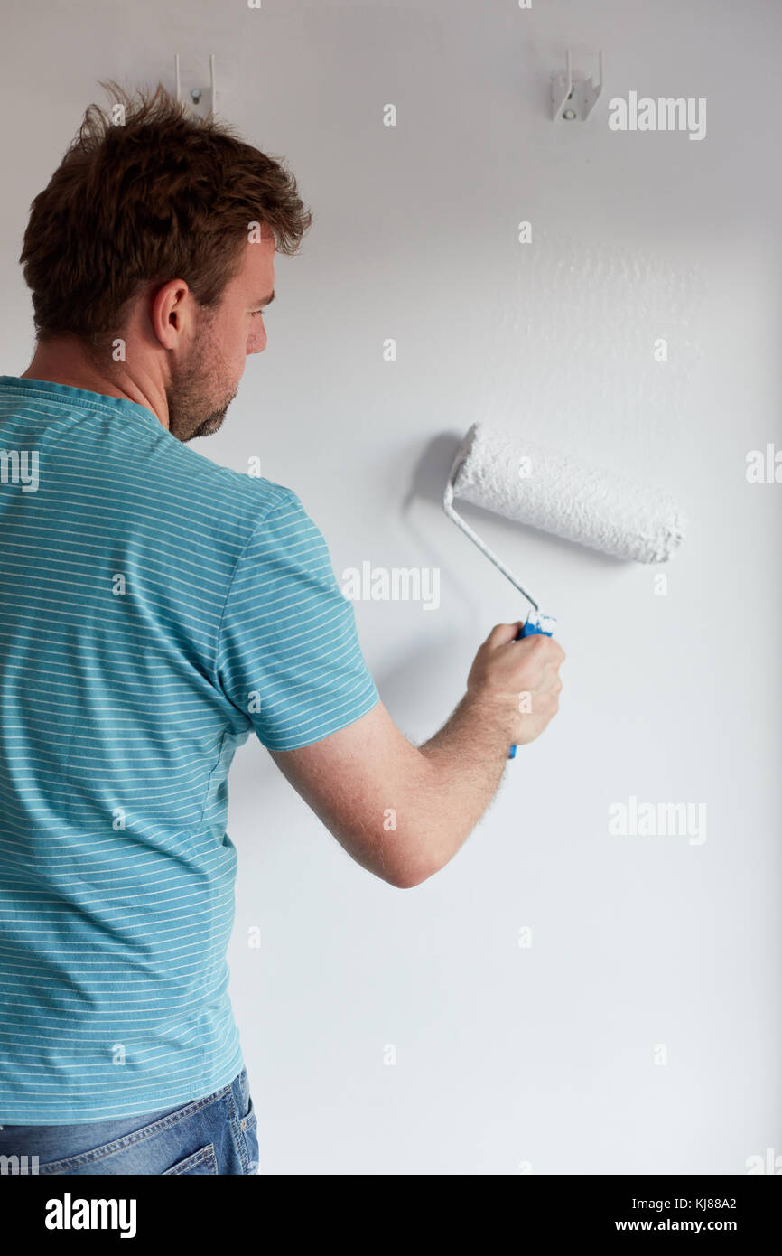 Young man painting a wall on white in a modern home Stock Photo - Alamy