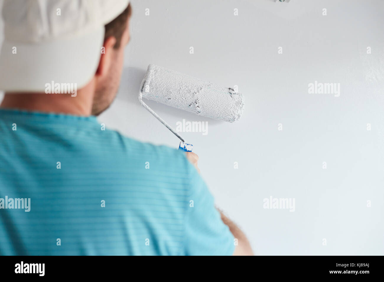 Young man painting a wall on white in a modern home Stock Photo - Alamy