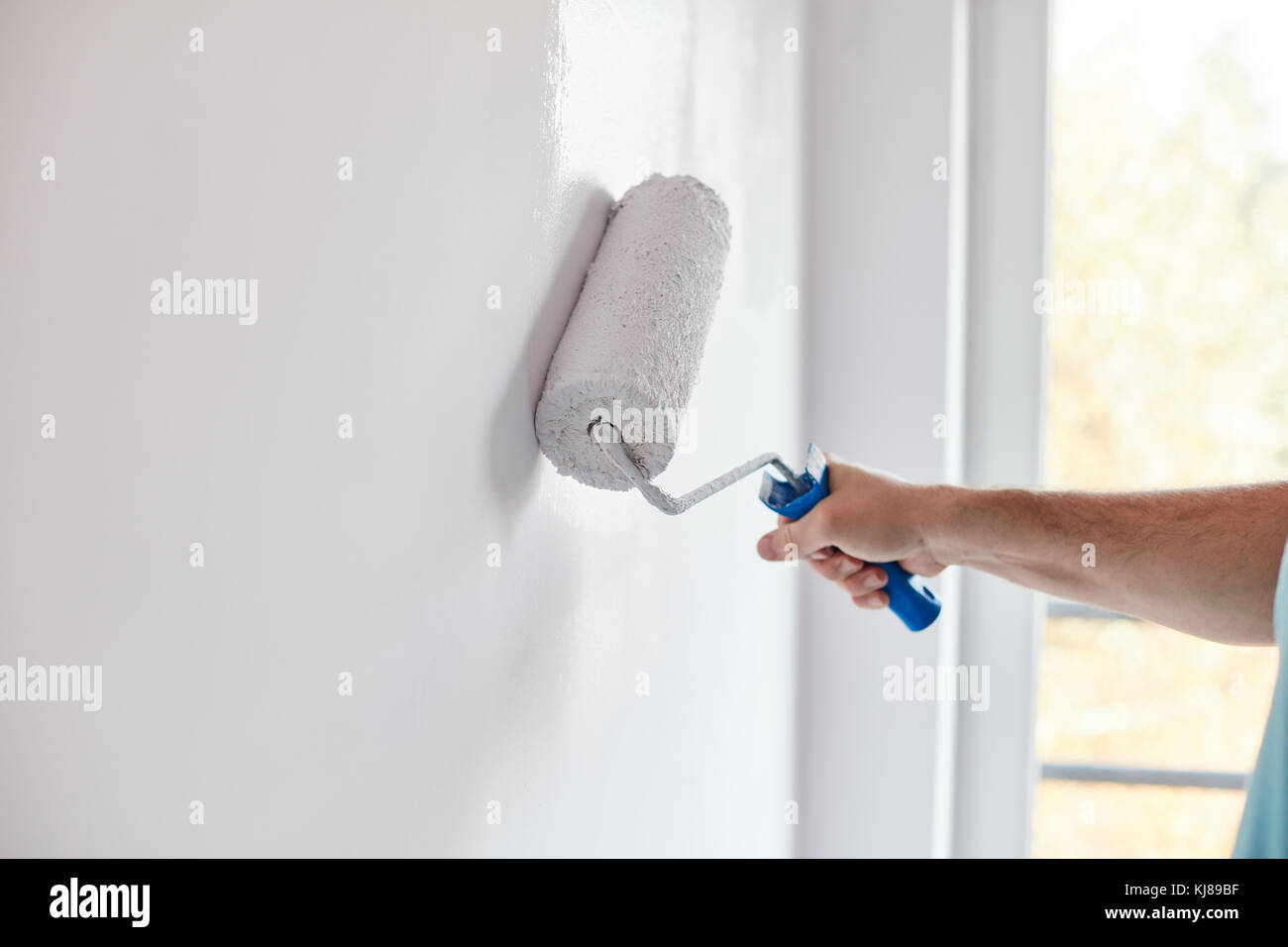 Male hand painting wall with paint roller. Painting apartment ...