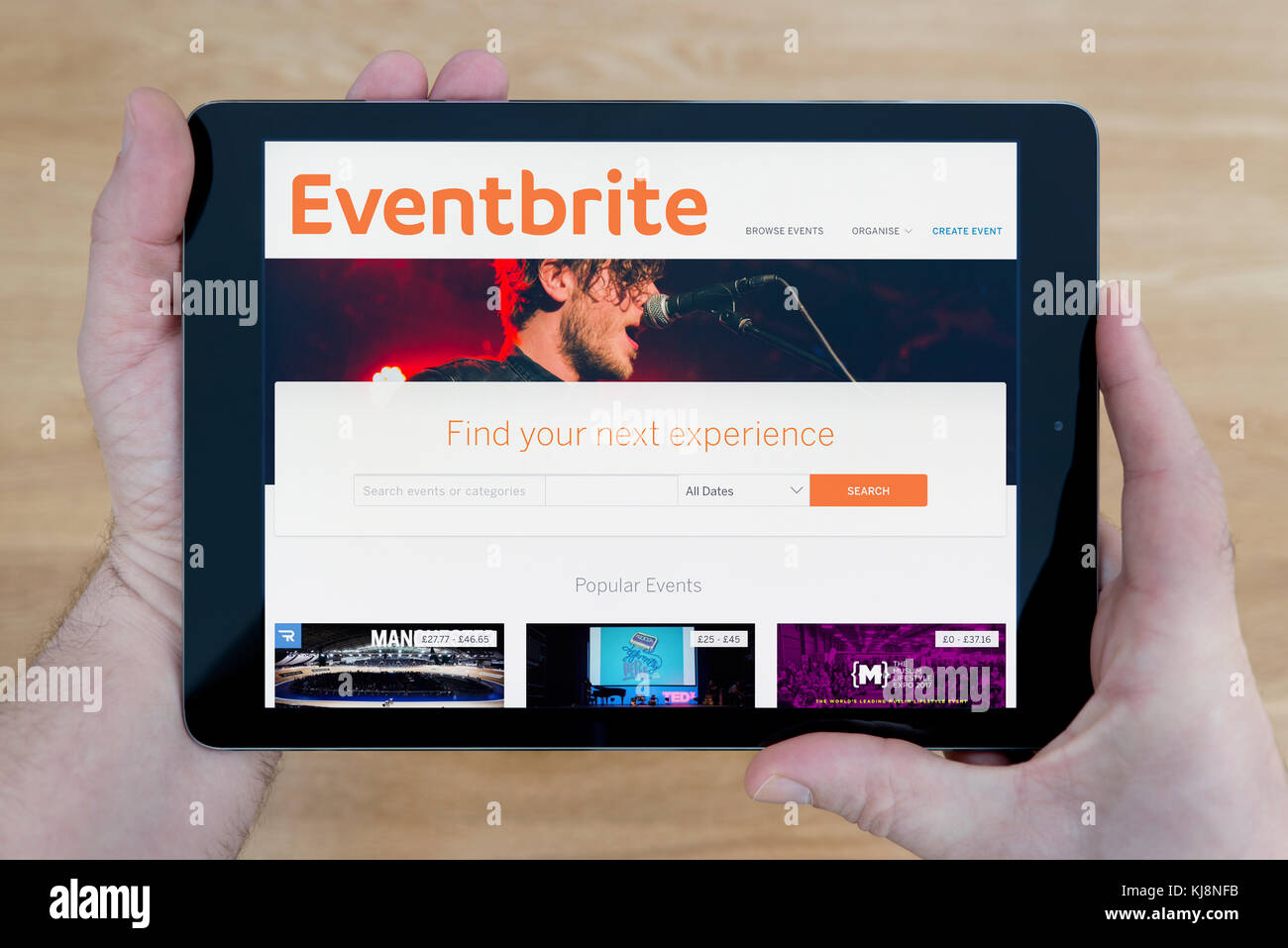 A man looks at the Eventbrite website on his iPad tablet device, shot ...