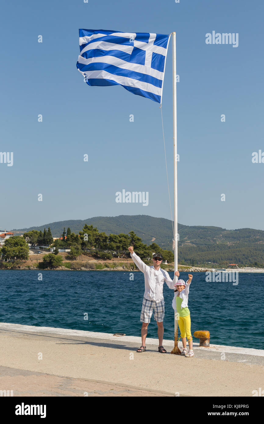 Tourists father and daughter near Greek flag on the Aegean coast of ...