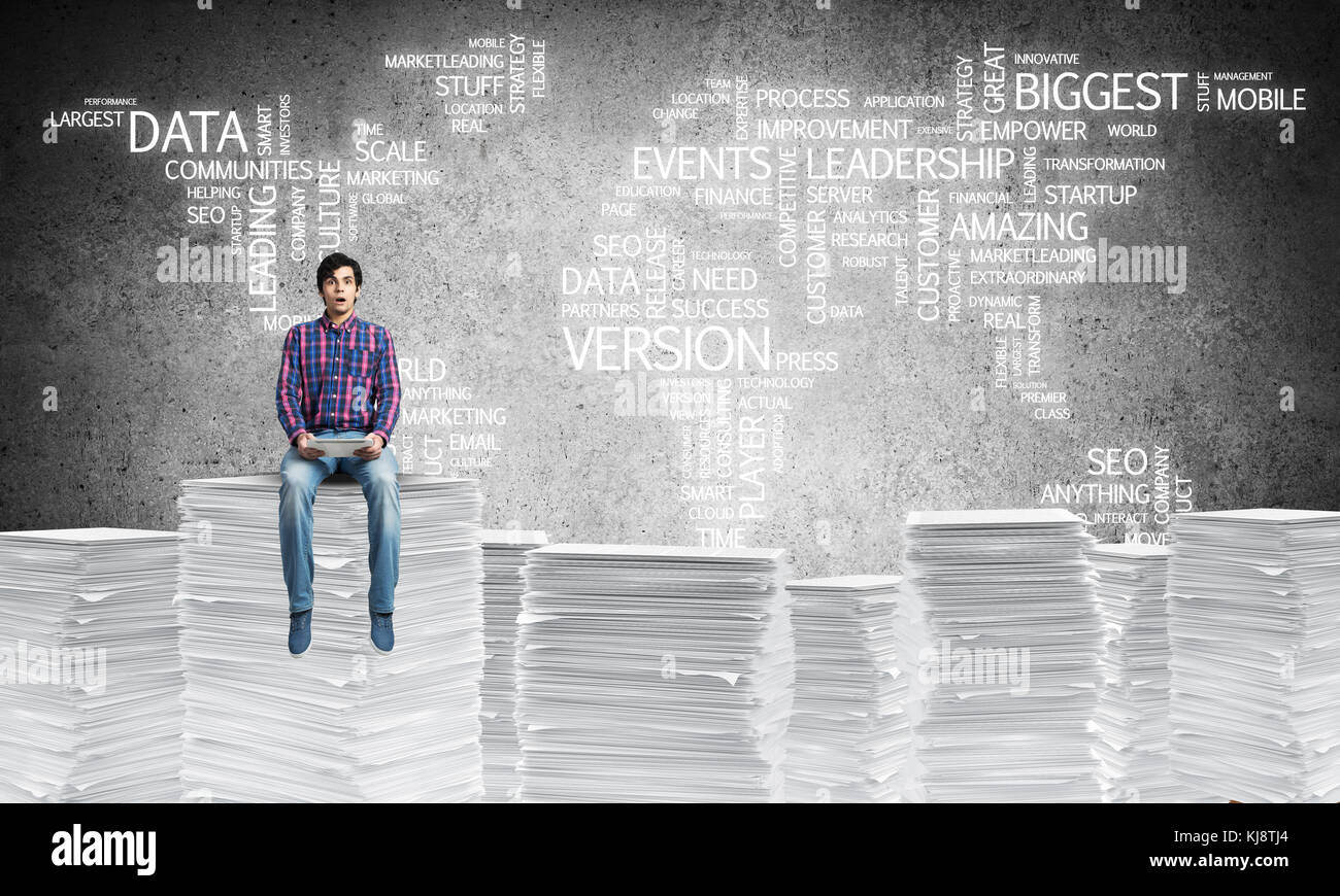Attractive man sitting on pile of paper documents Stock Photo - Alamy