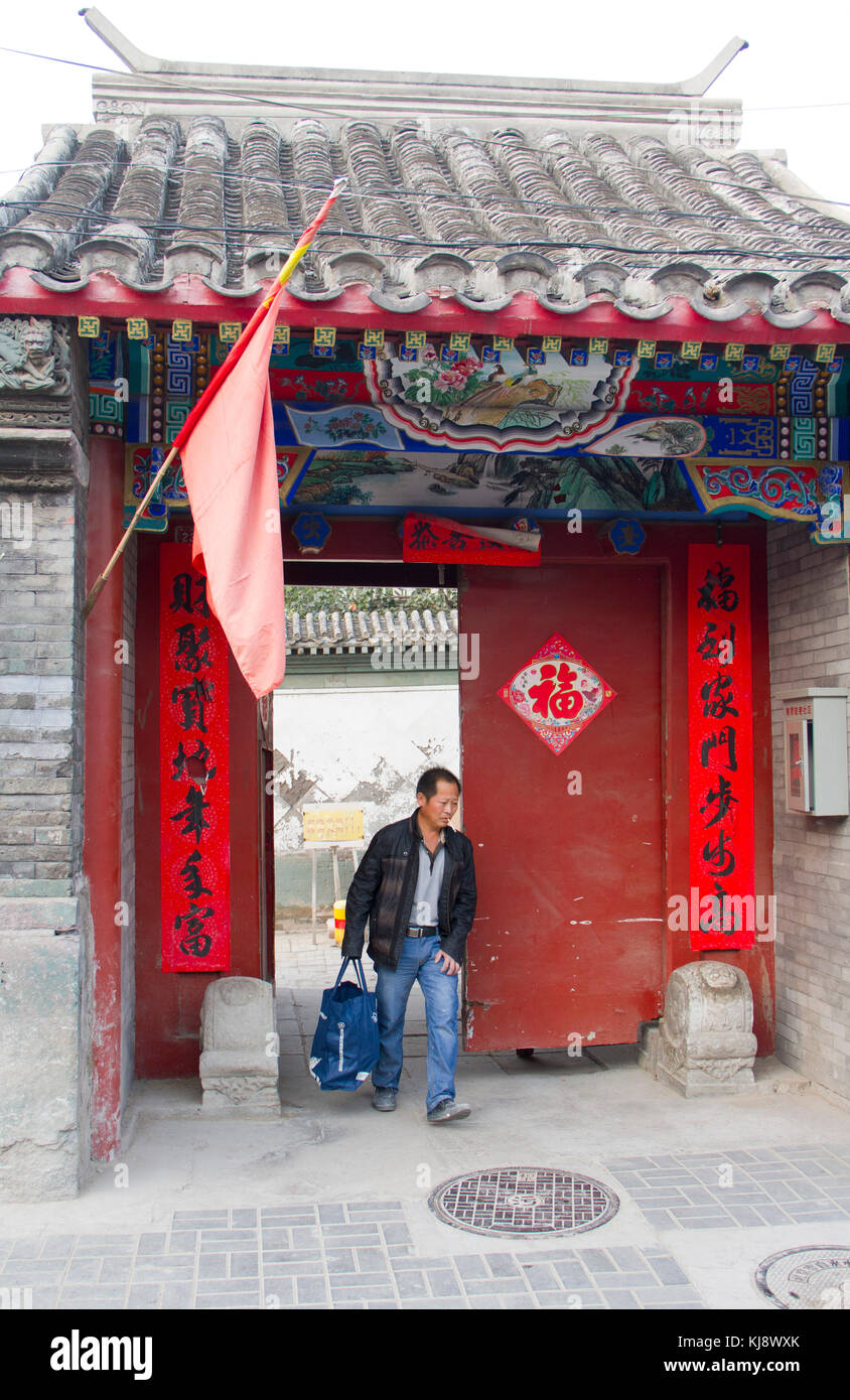 A man walk through a gate in historic alleyways that branch off Bejing ...