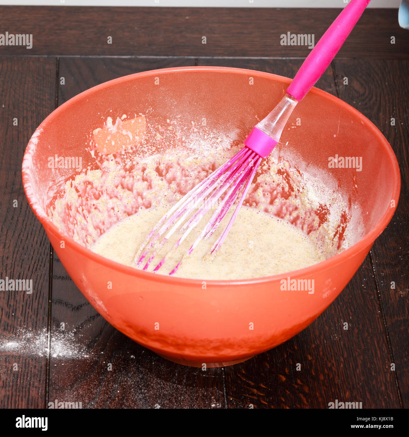 Cooking in kitchen. Orange plastic bowl with undone liquid cake and ...
