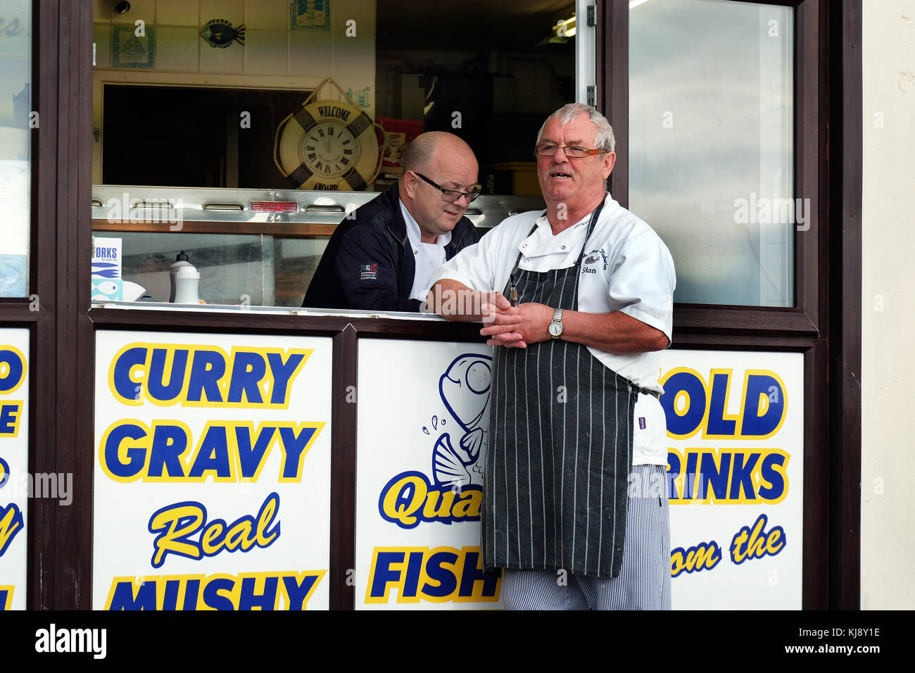 Two owners outside fast food fish and chip business Stock Photo - Alamy