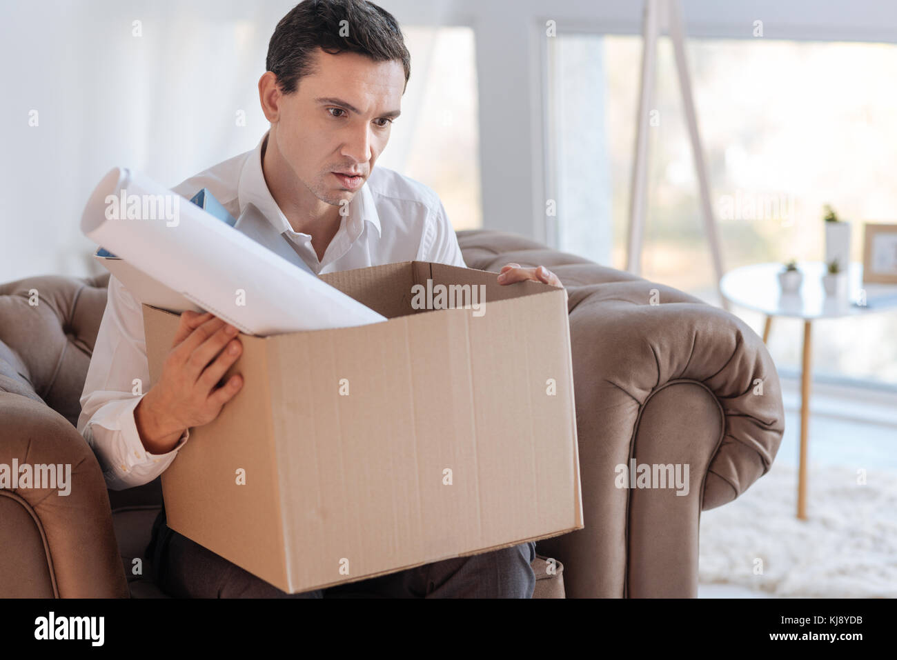 Shocked young man sitting with a box after losing his job Stock Photo ...