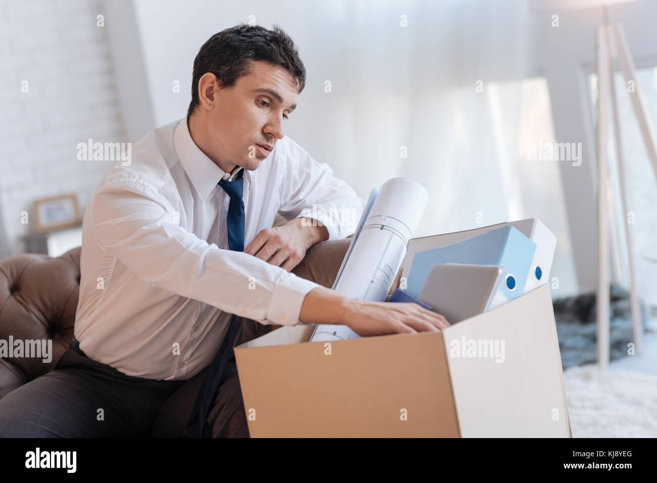 Calm elegant man looking at his personal things after dismissal Stock ...